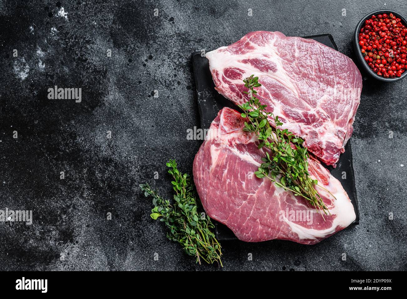 Raw pork meat steaks on a marble board. Black background. Top view ...