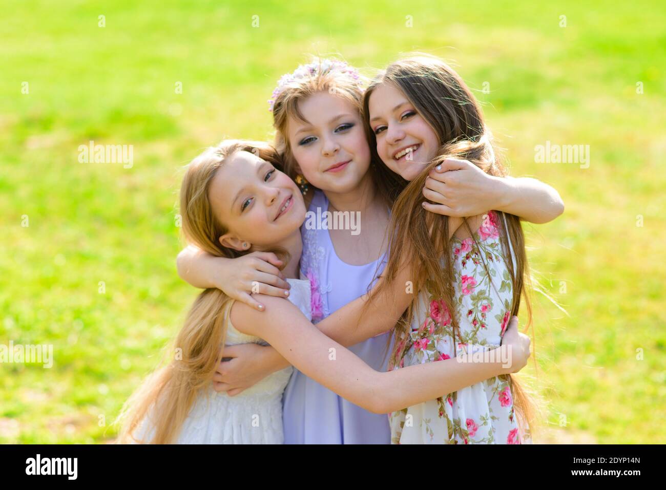 Three beautiful girls in retro dresses for a walk in a flowered garden ...