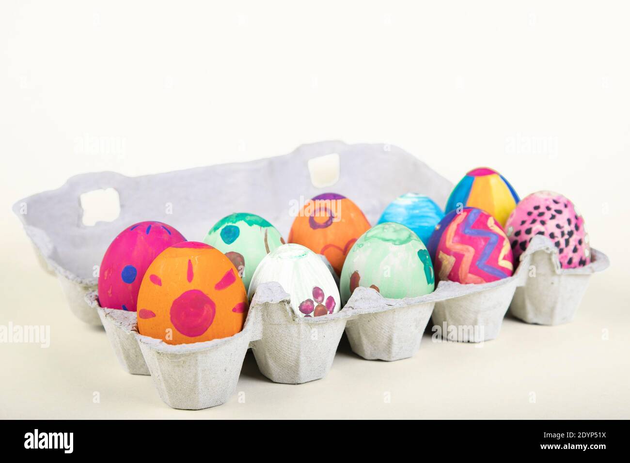 painted eggs with easter motives in an egg carton, white background ...