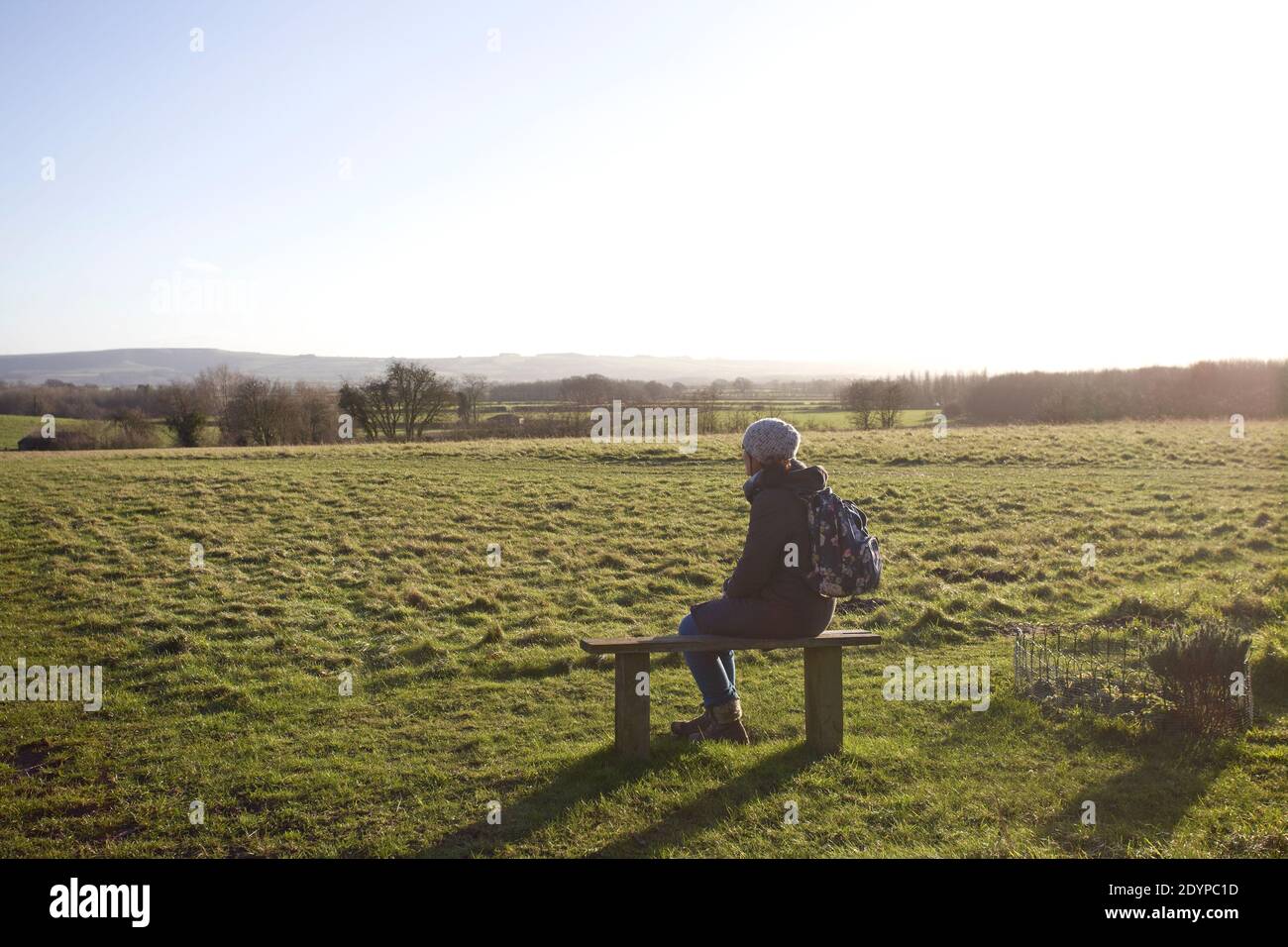 Young woman sat on bench relaxing in the winter sunshine, Oxfordshire ...