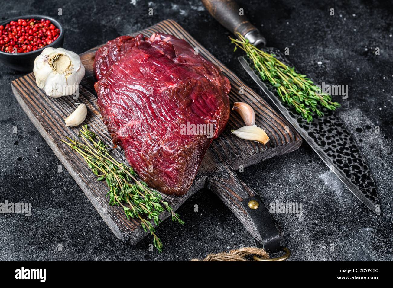 Venison raw deer meat on a cuuting board with herbs. Black background ...