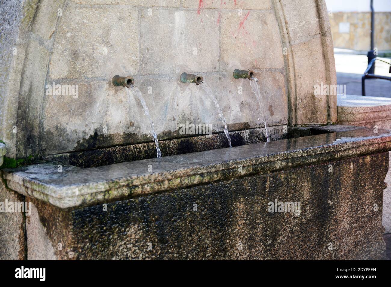 Stone fountain with three water pipes. Natural water flowing from a ...