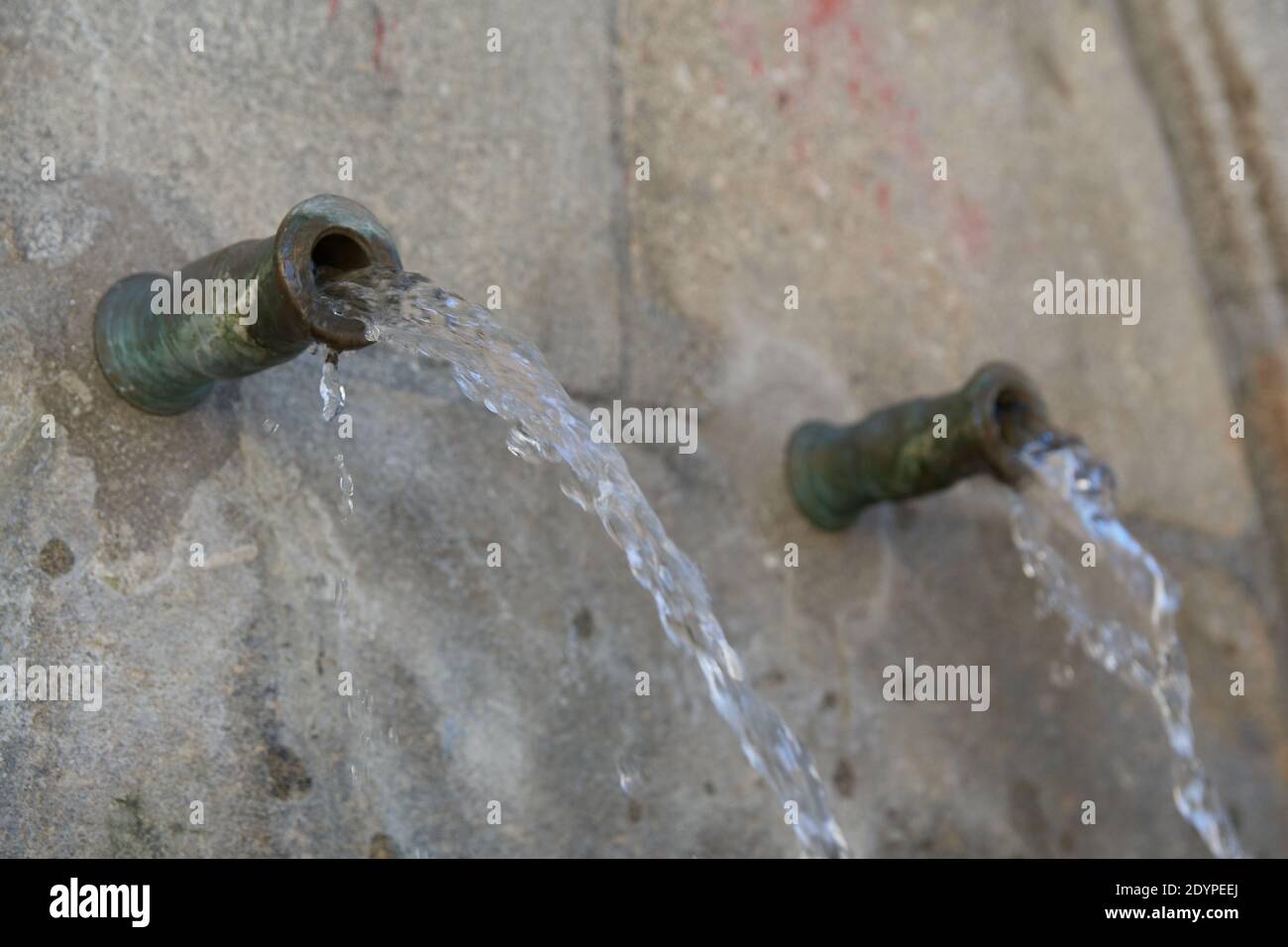 Stone fountain with three water pipes. Natural water flowing from a ...