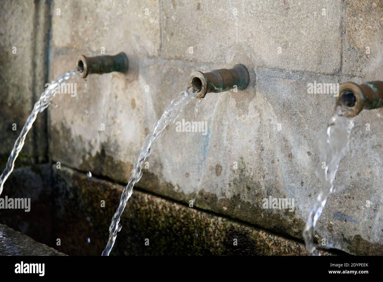 Stone fountain with three water pipes. Natural water flowing from a ...