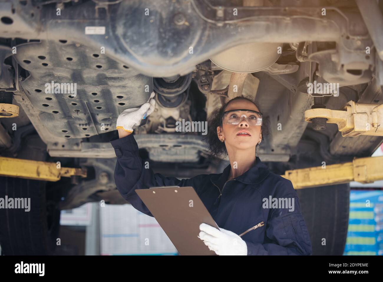 Female mechanic inspecting a lifted car Stock Photo - Alamy