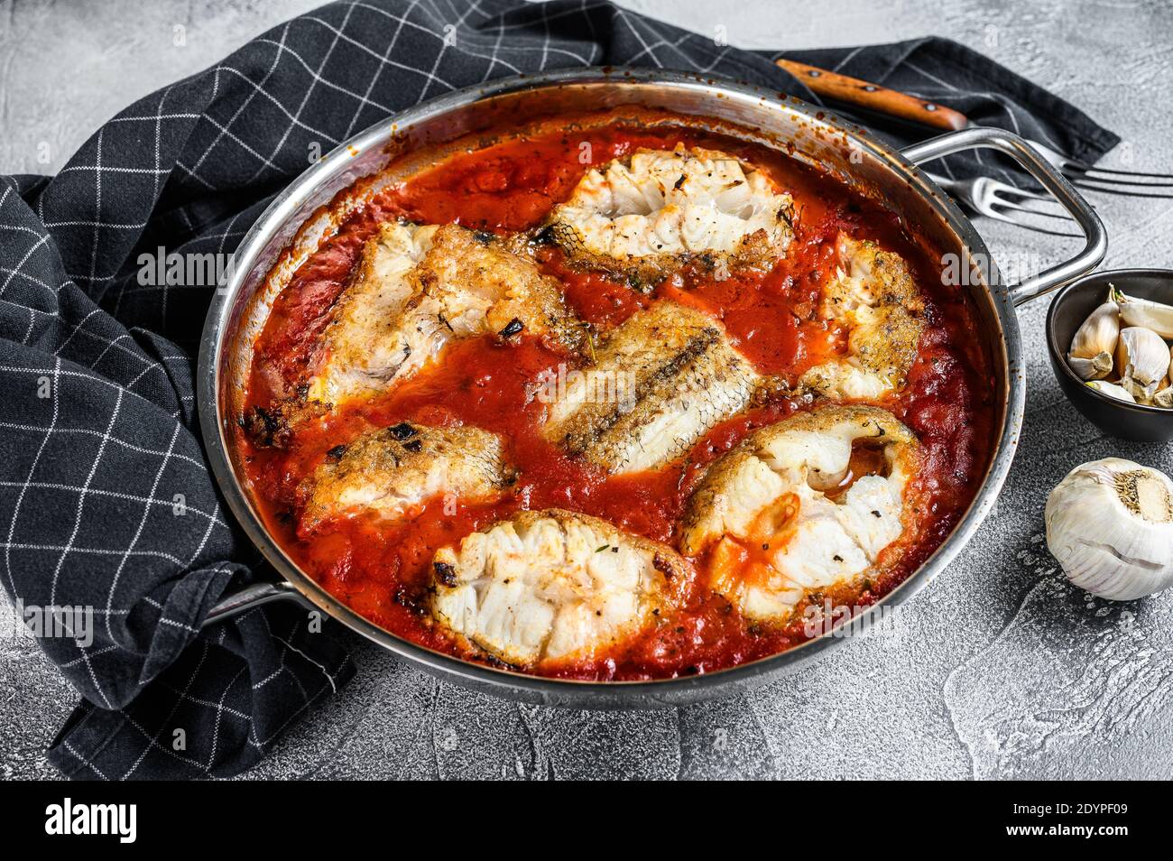 Baked grenadier macrurus white fish with tomato in a pan. White Wooden ...