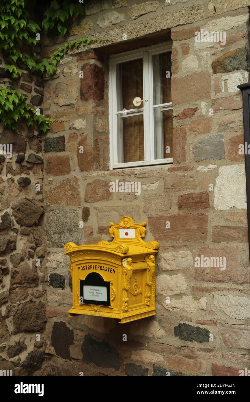 Old and antique yellow letterbox hung on the wall of an old German ...