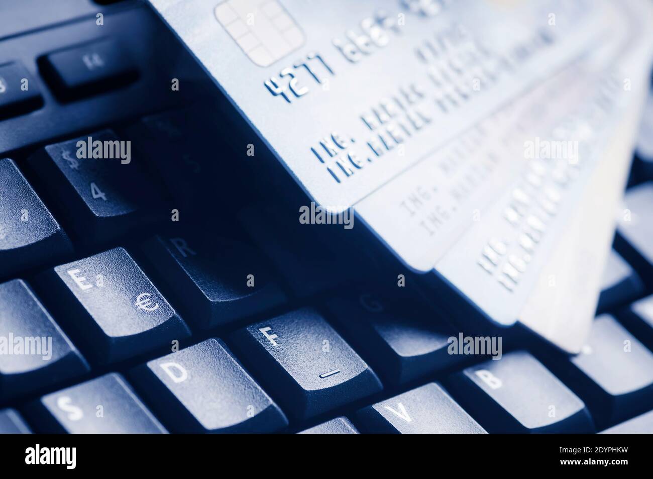 Four credit cards on blue computer keyboard. E-commerce data and ...