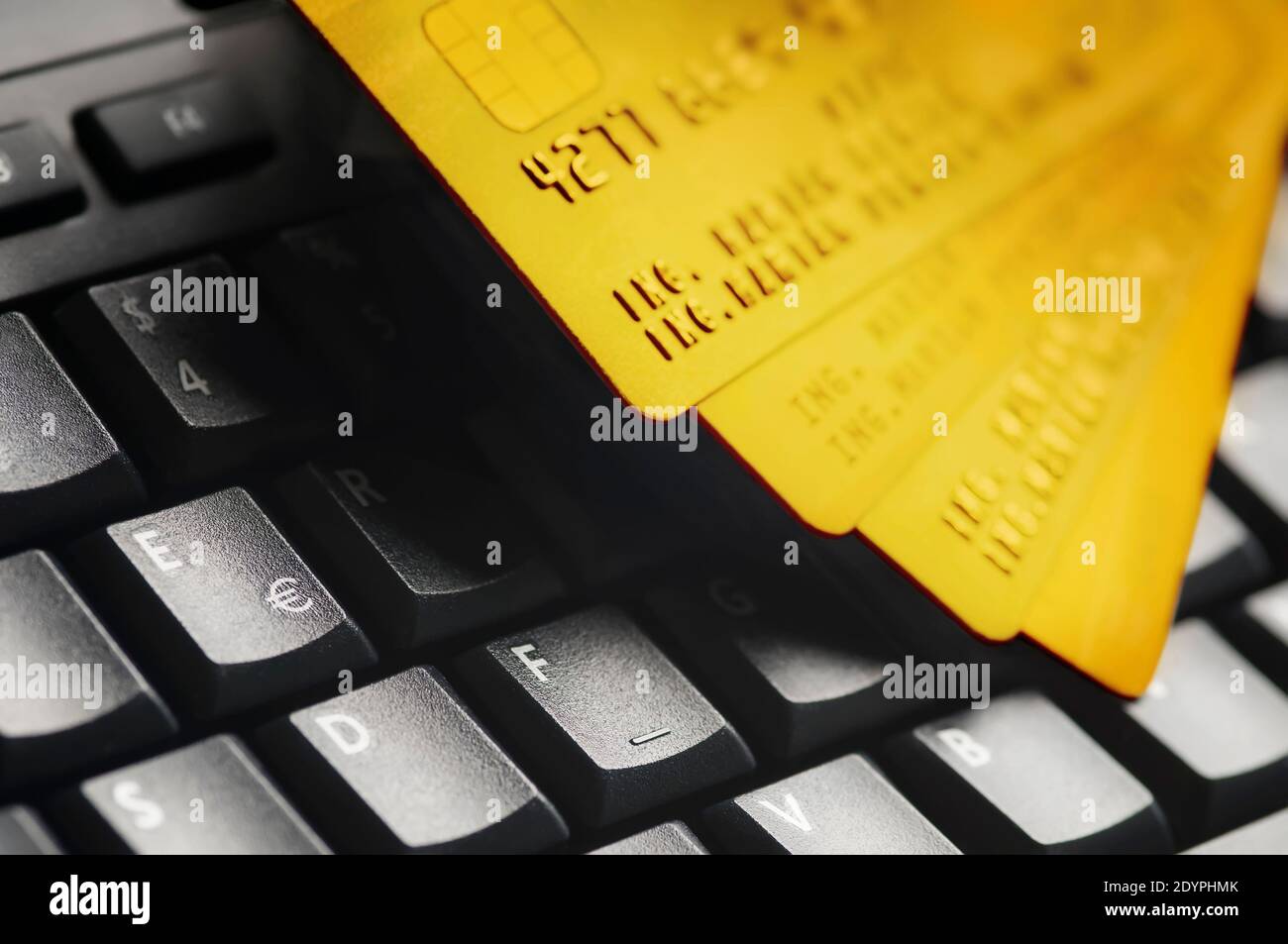 Four golden credit cards on black computer keyboard. E-commerce data ...