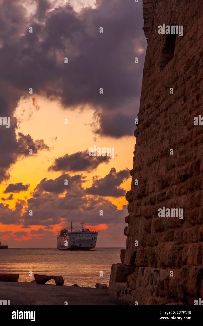 Ship arriving to the port of Heraklion, Crete during a cloudy sunrise ...