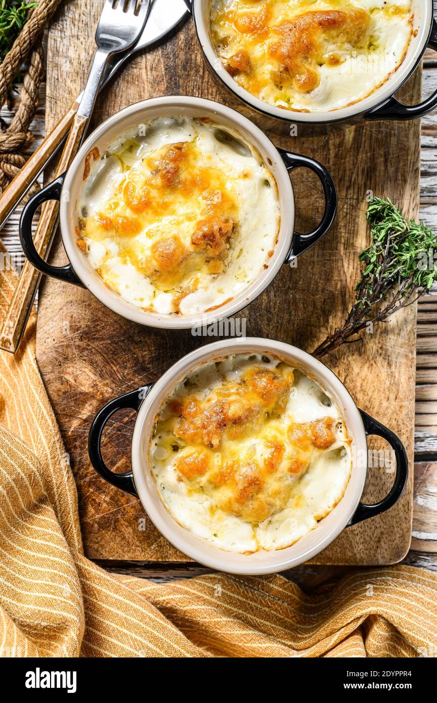 Julienne with chicken and cheese in portion forms on a wooden table ...