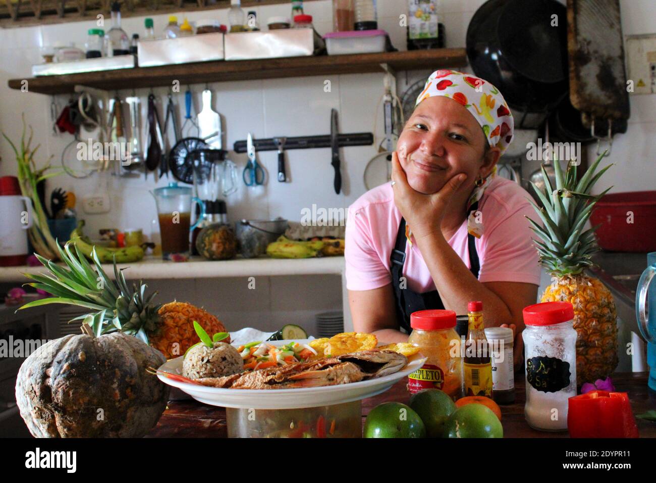 Woman smiling while cooking with many fruits and vegetables around ...