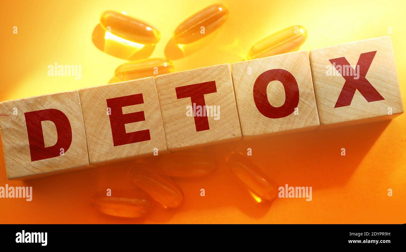 Detox word made with wooden blocks and oil capsuless around on orange ...