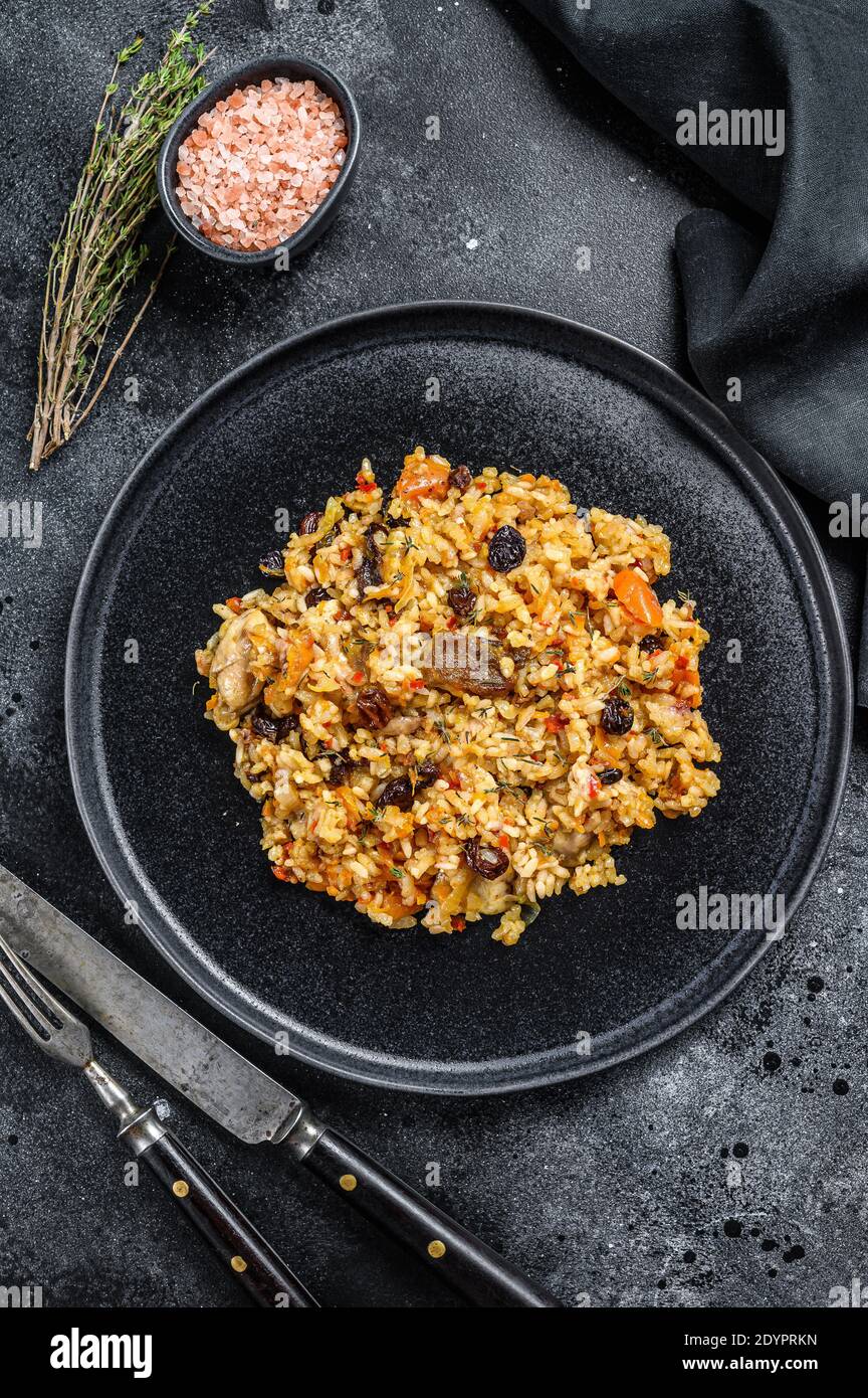 Uzbek pilaf made from beef, lamb, chicken, in large plate. Dark ...