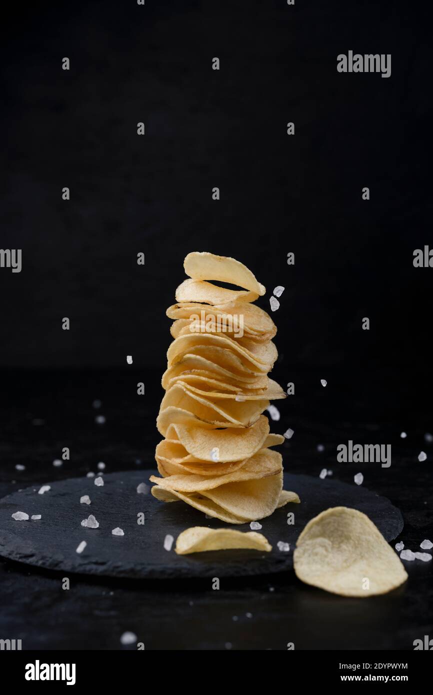 Potato chips and salt in composition on black background Stock Photo ...