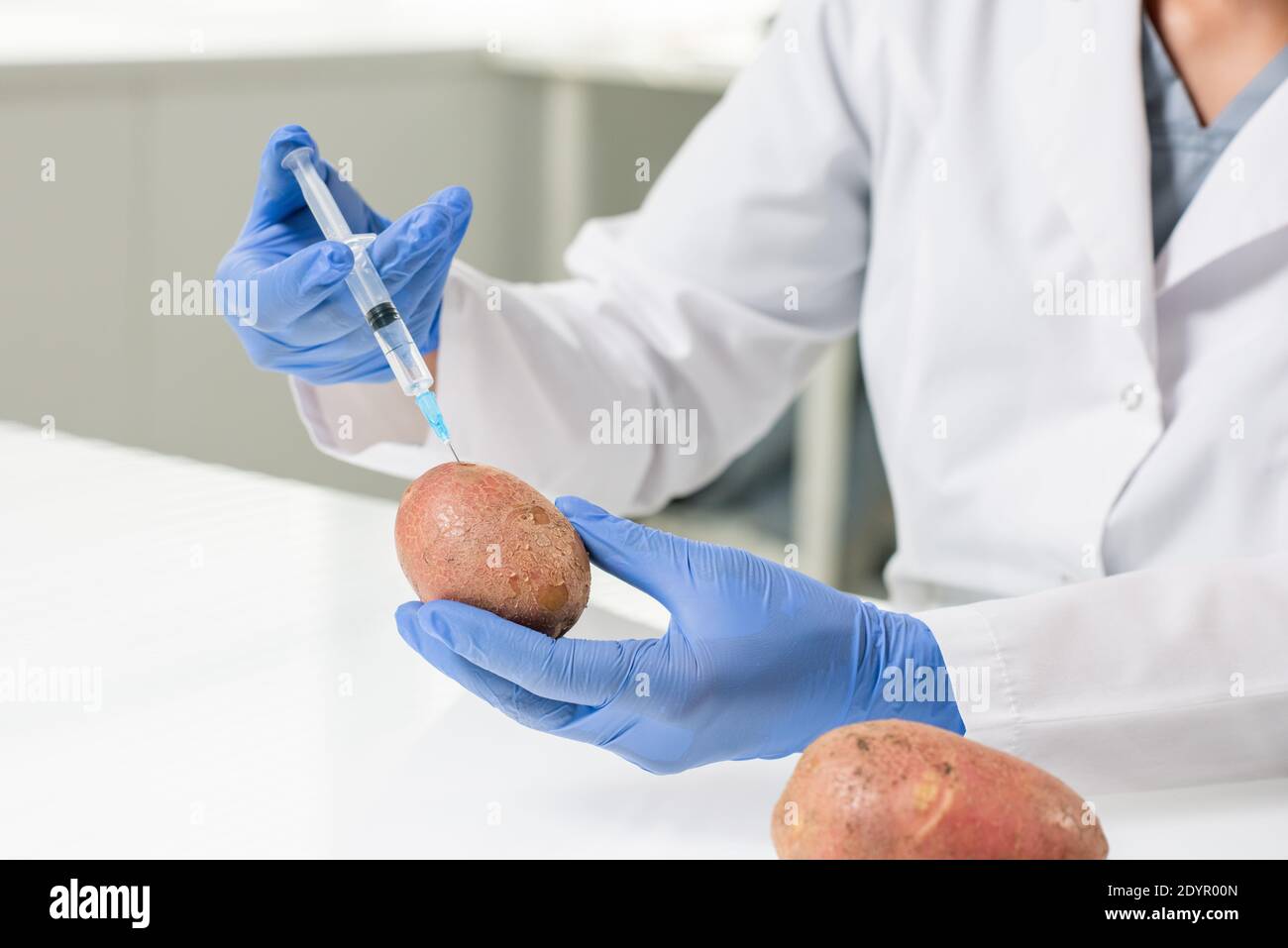 Young scientist or researcher in whitecoat and gloves sitting by ...