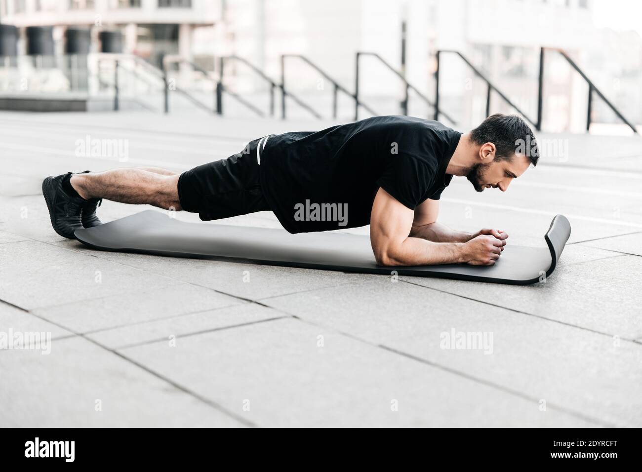 Plank it Training in big city concept. Sporty young man wearing black ...