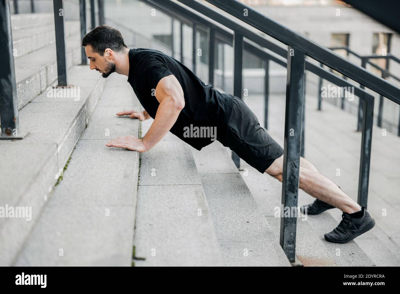 Well built young man pushing up from stairs. Side view. Athletic man ...