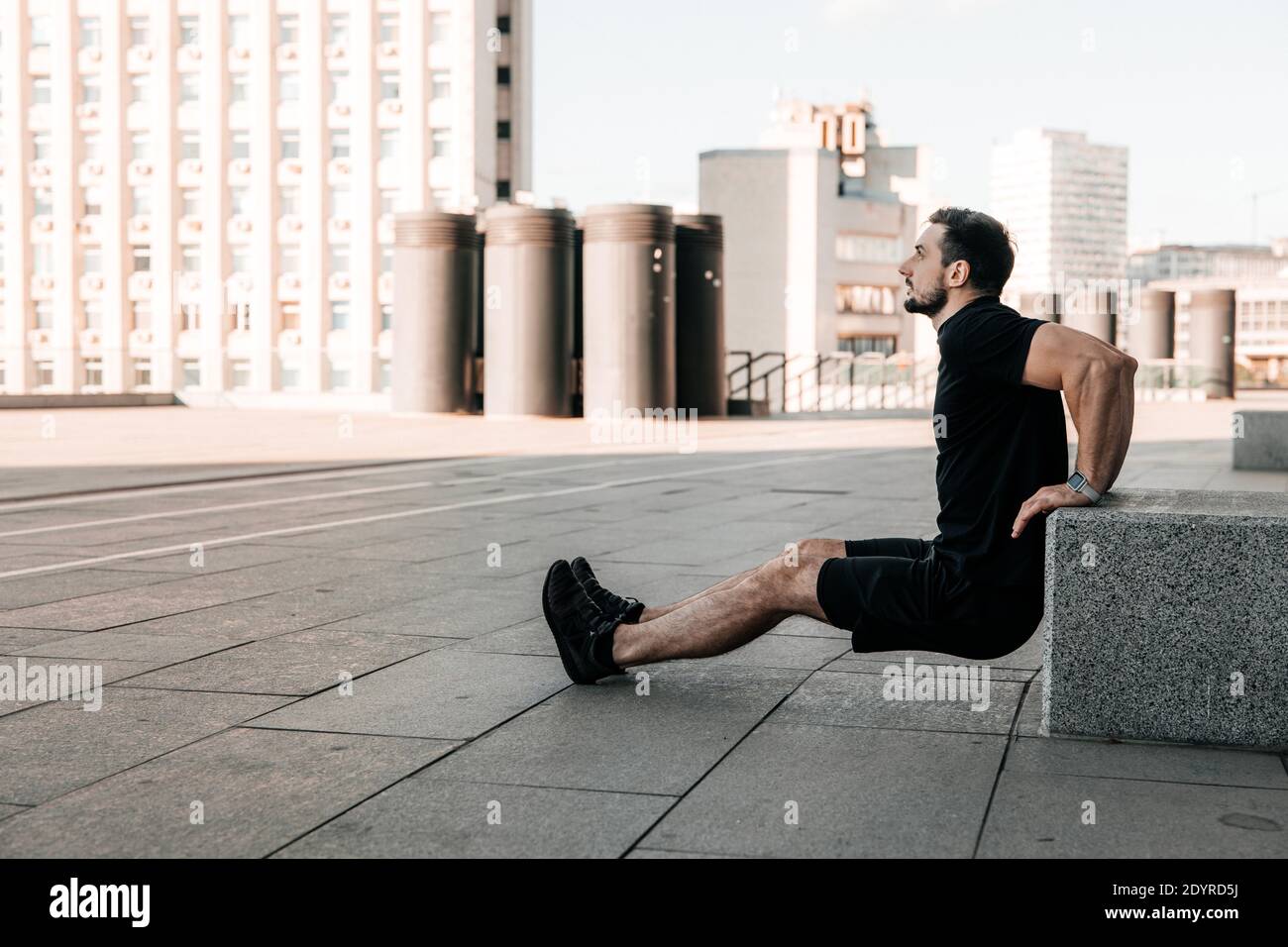 Fit man pushing from stone cube. Morning workout outdoors. Black ...