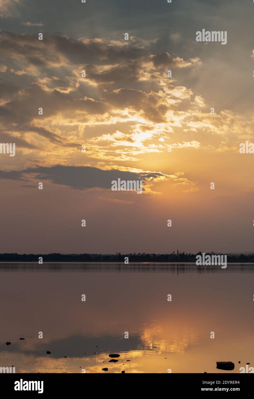 Sunset with clouds on the sky reflected on water Stock Photo - Alamy