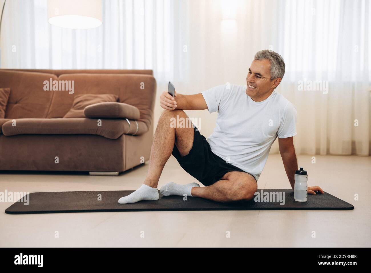 Procrastination during fitness. Senior man resting after home workout ...