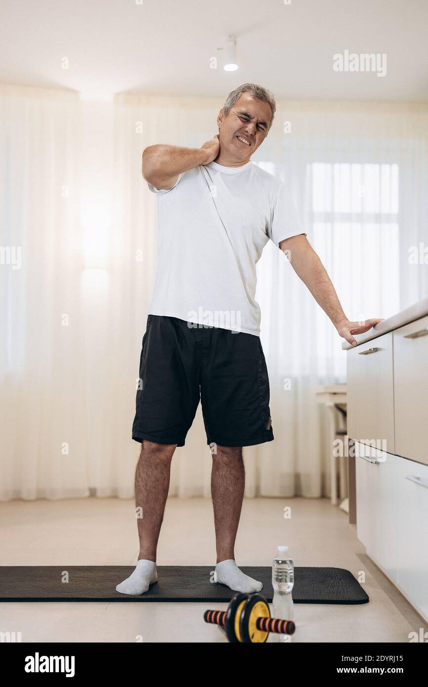 Neck muscular spasm during training. Elderly man touching upper back ...