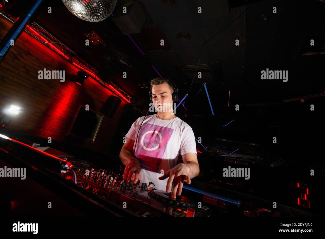 Male DJ in stylish white t-shirt mixing music at party. Nightlife ...