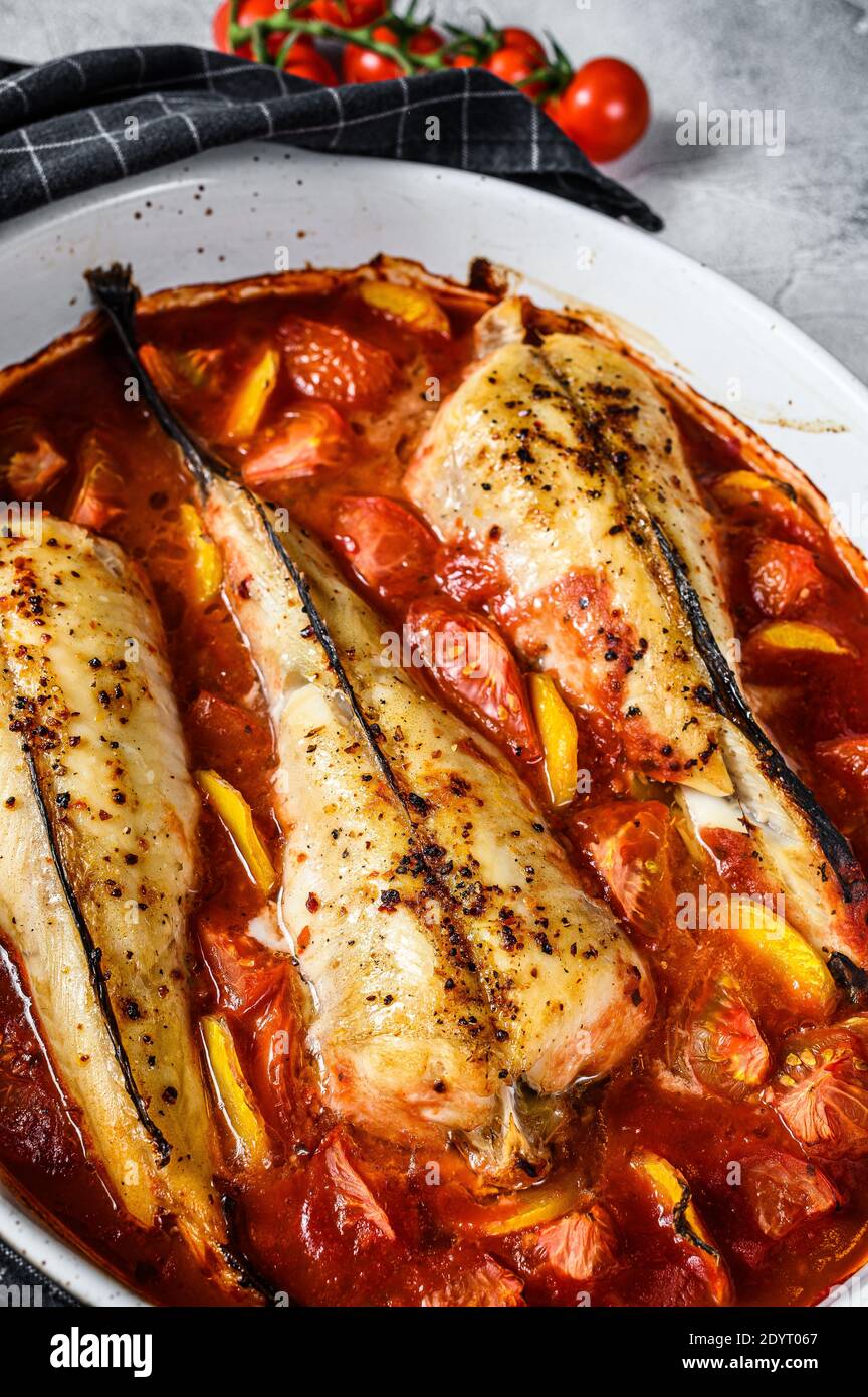 Cooking in tomatoes monkfish fish in a baking dish. Fresh seafood. Gray ...