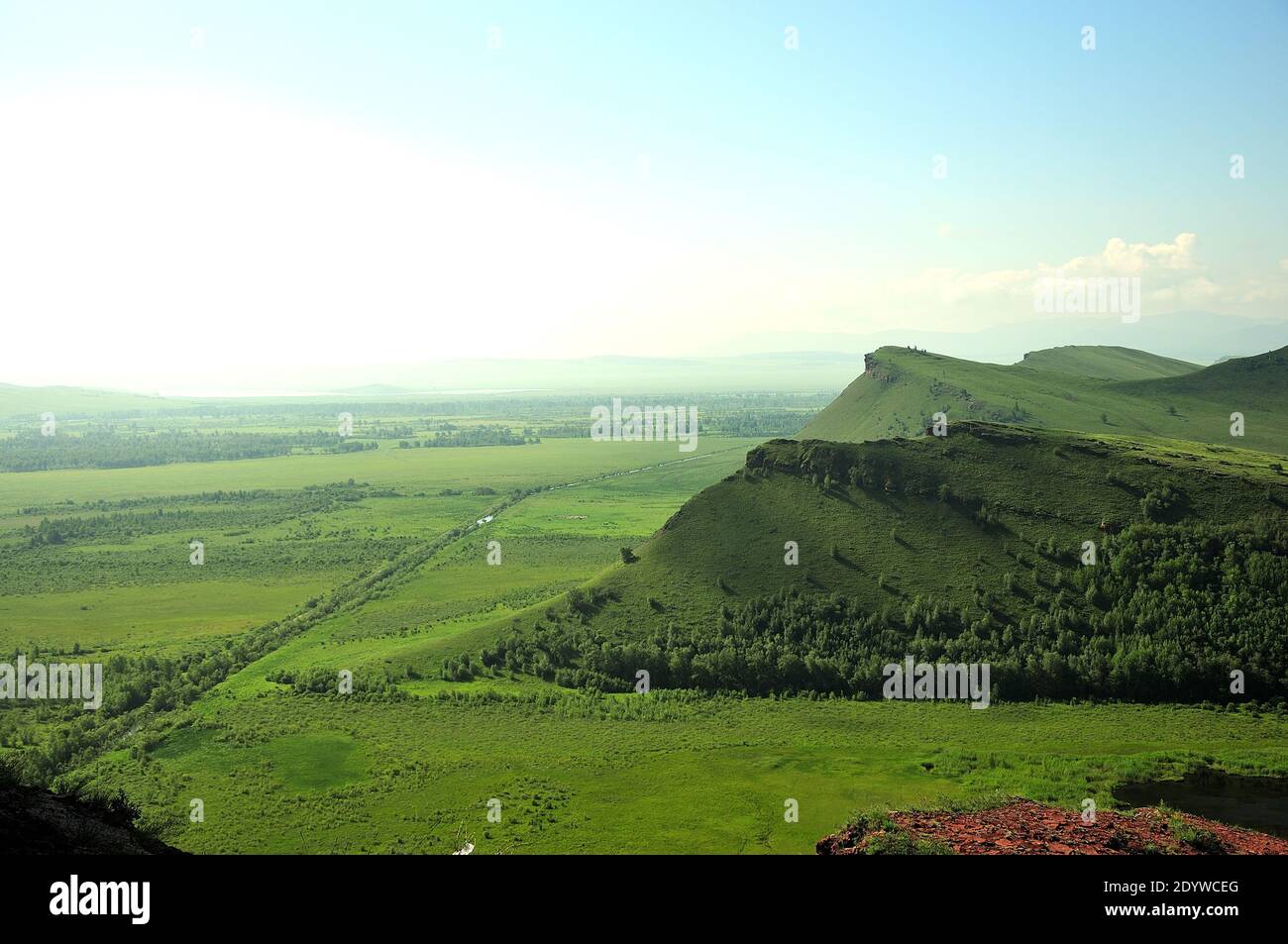 A mountain range standing in the endless steppe with rare bushes and ...