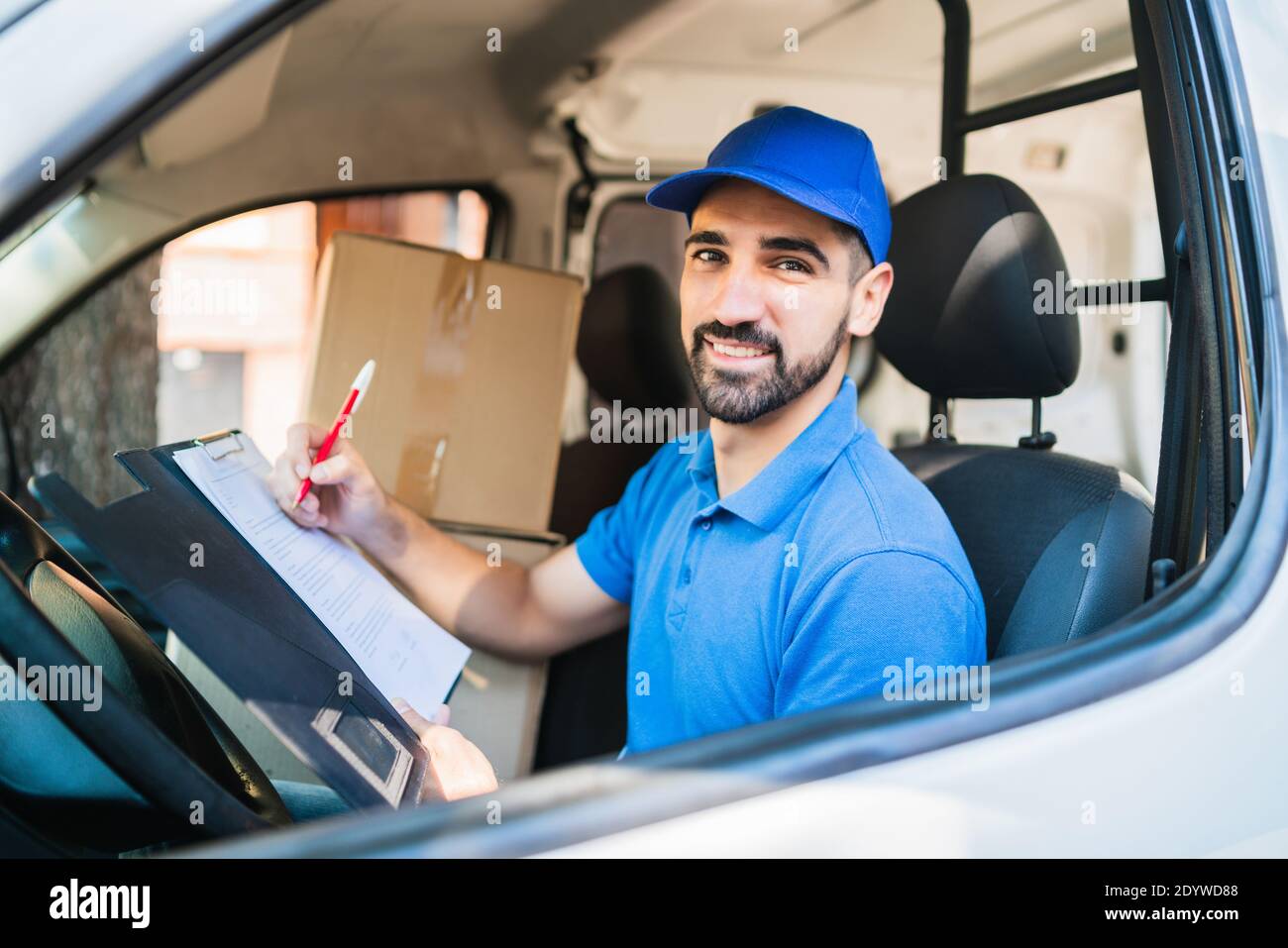 Delivery man checking delivery list in van Stock Photo - Alamy