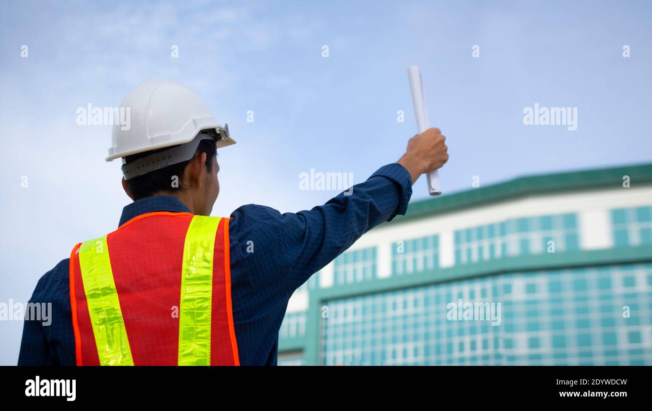 Engineer holding paper plan against building sky background Stock Photo ...