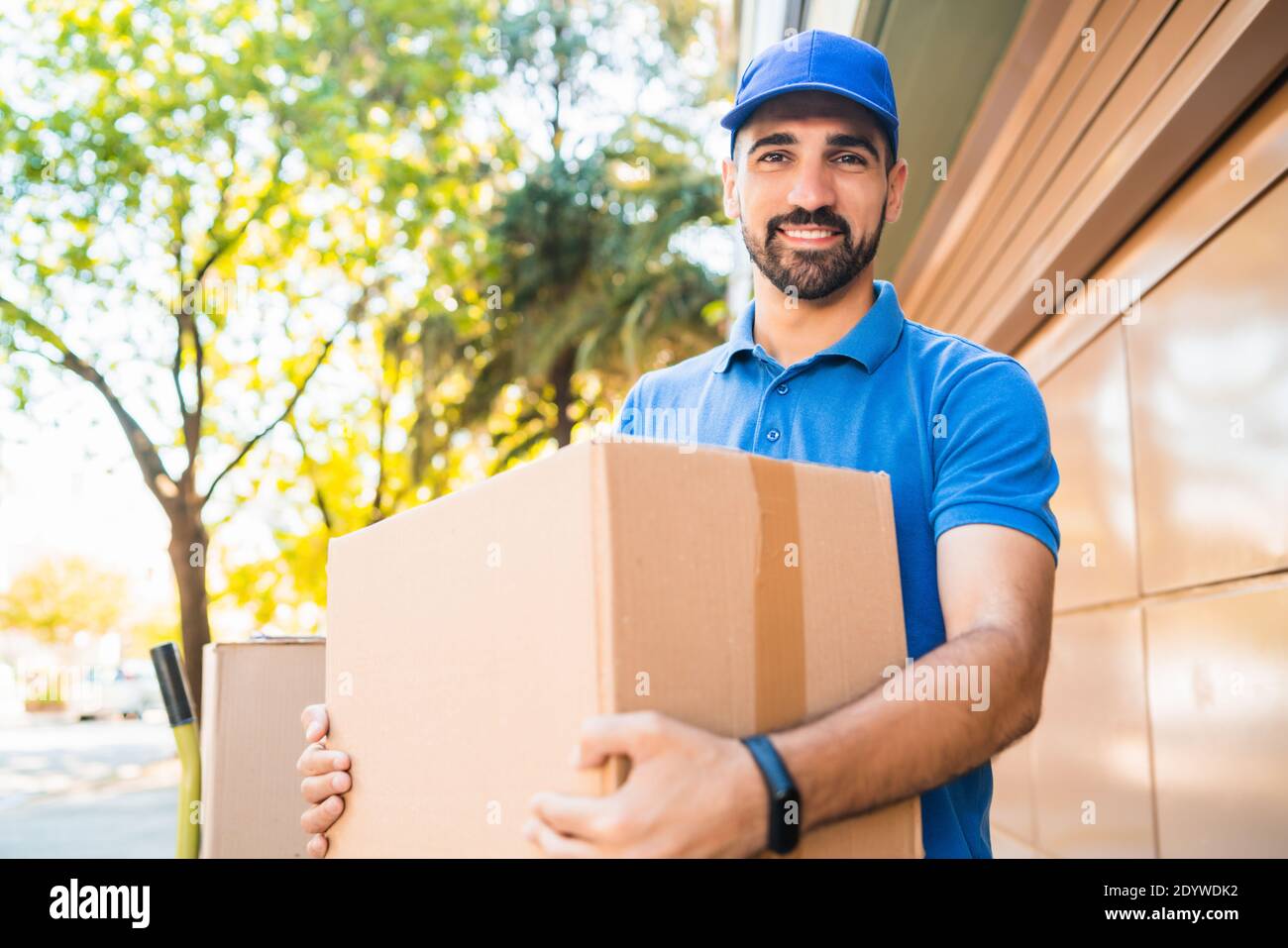 Delivery man carrying package outdoors Stock Photo - Alamy