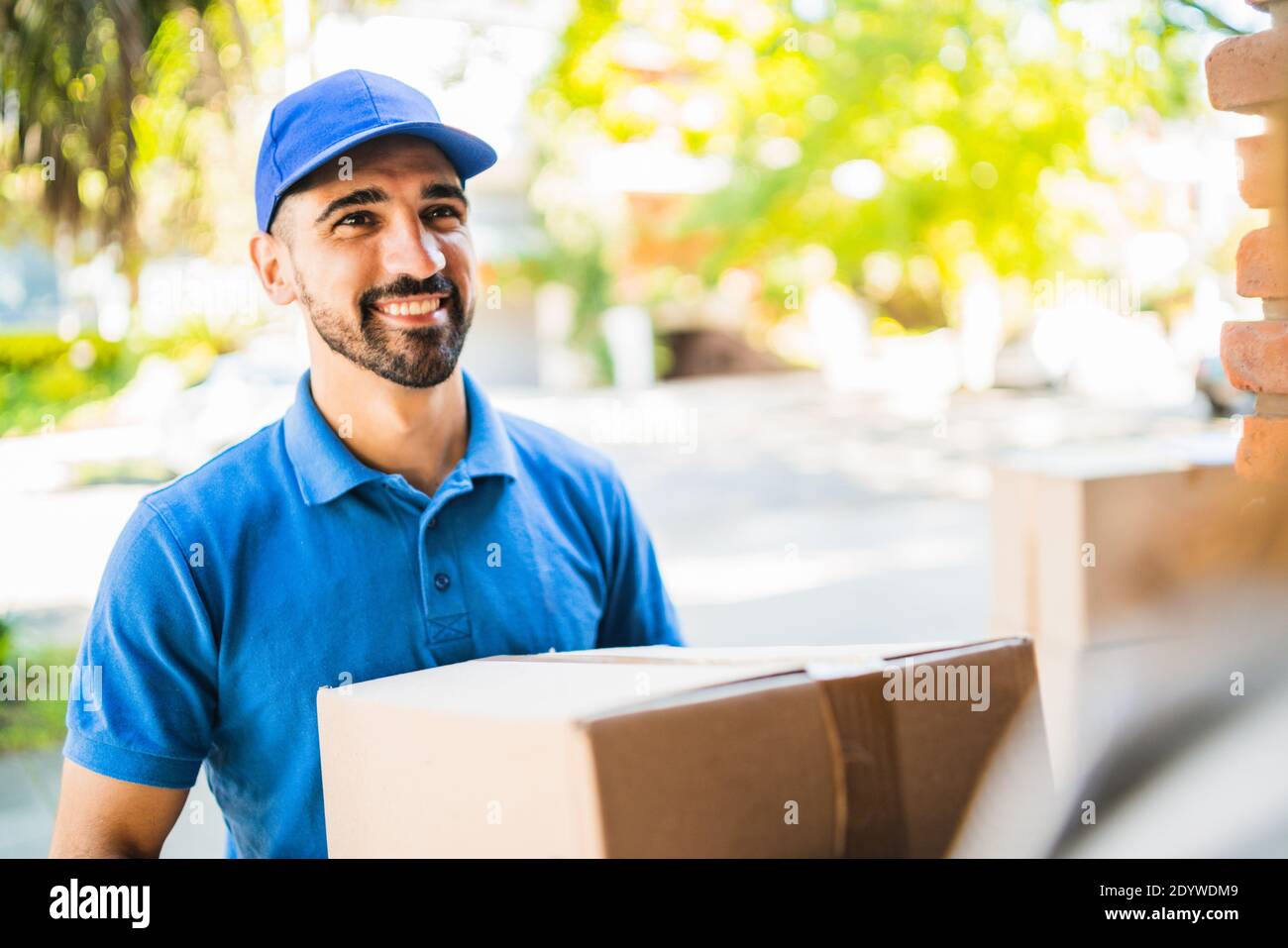 Delivery man carrying packages while making home delivery Stock Photo ...