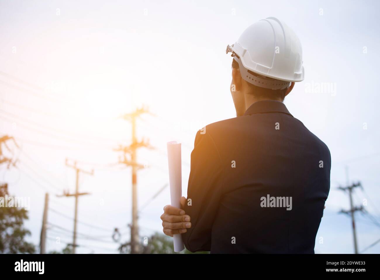 Engineer holding paper electric pole background Stock Photo - Alamy