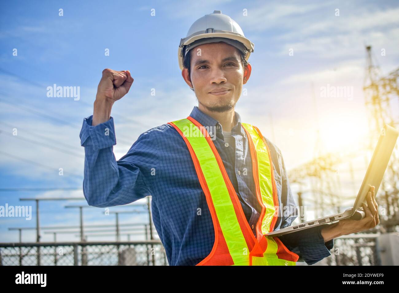 Engineer holding Computer notebook or laptop and a power plant with the ...