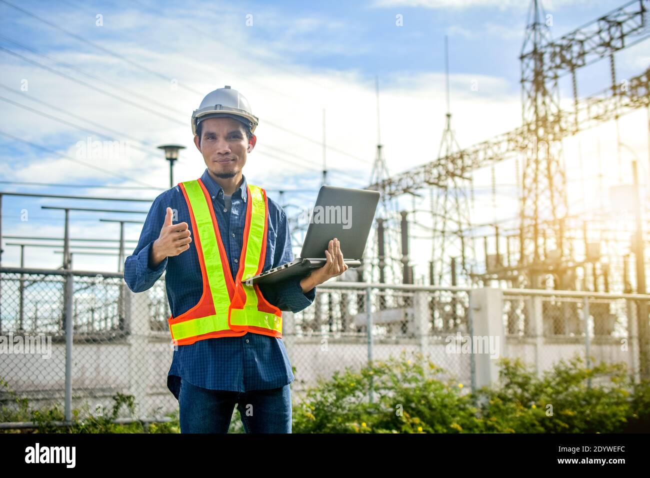 Engineer holding Computer notebook or laptop and a power plant with the ...
