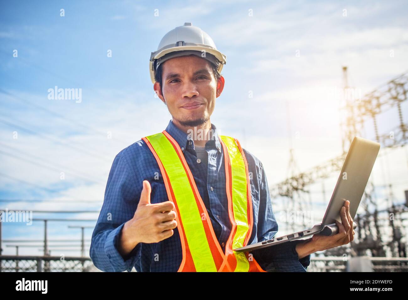 Engineer holding Computer notebook or laptop and a power plant with the ...