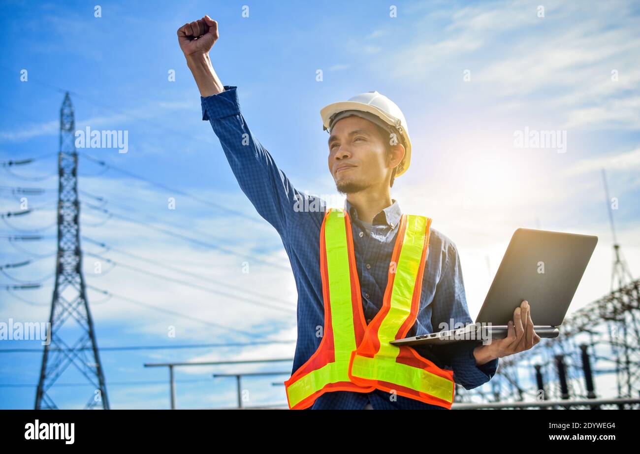 Engineer holding Computer notebook or laptop and a power plant with the ...