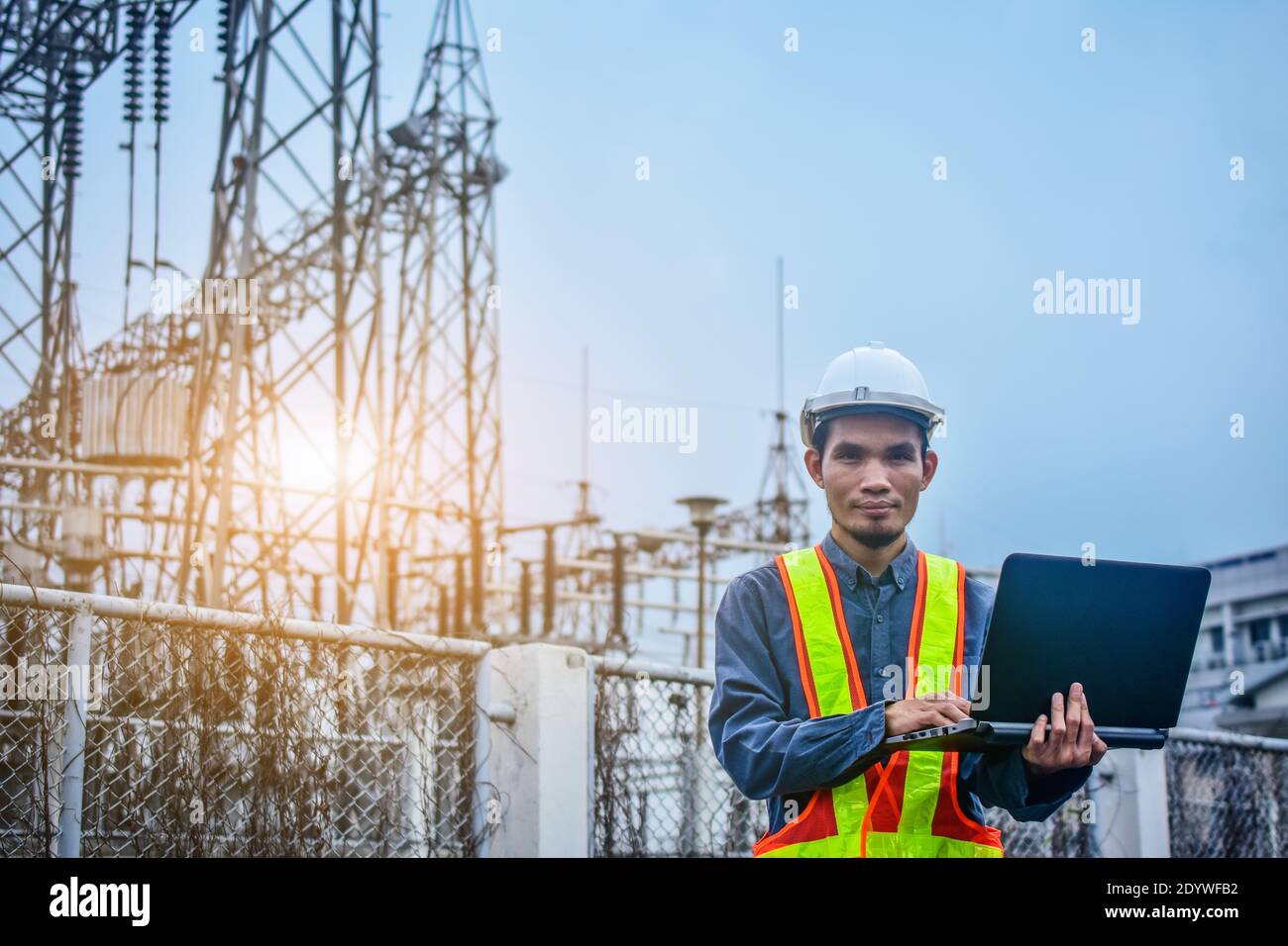 Engineer holding computer notebook high voltage power plant background ...