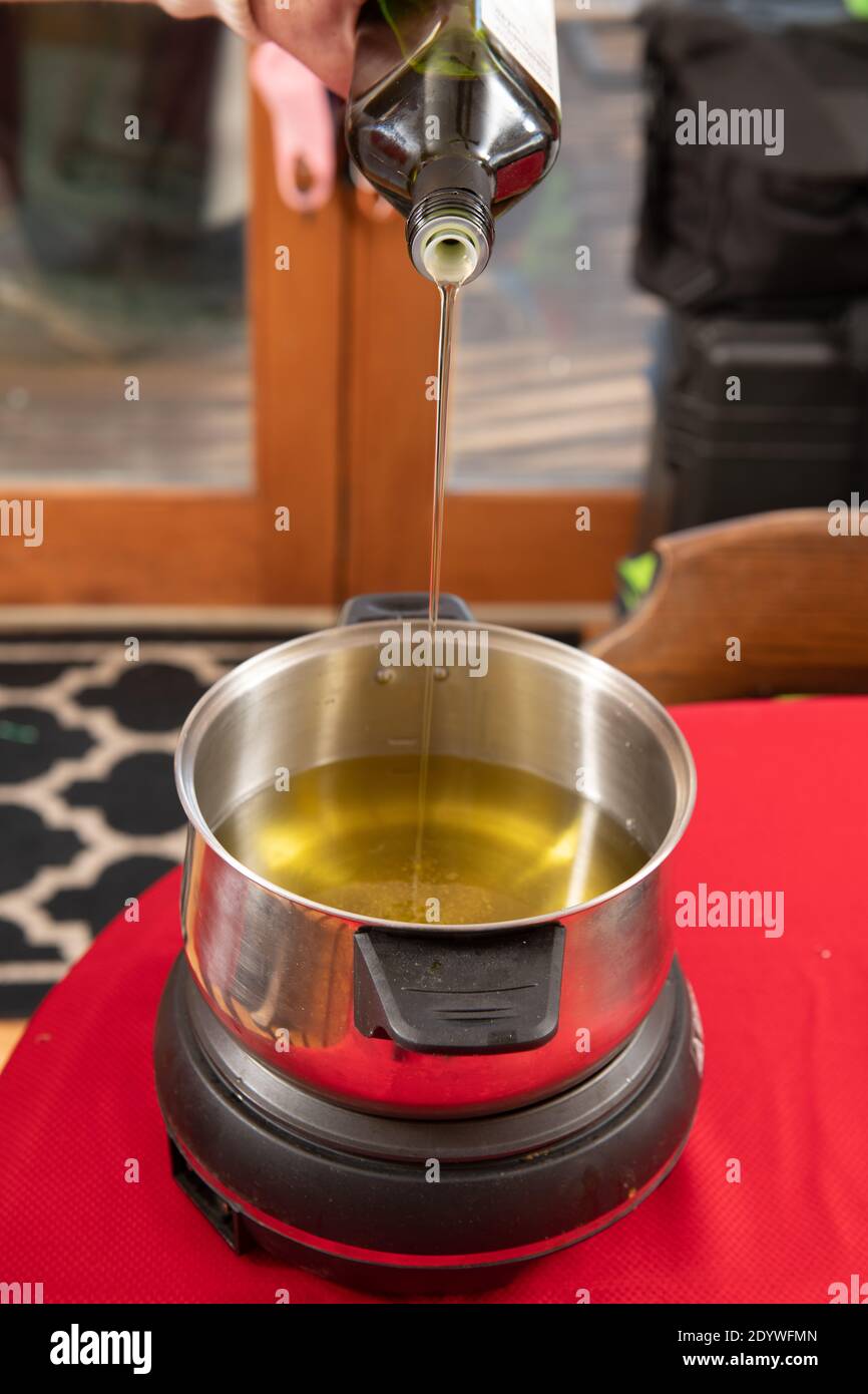 Oil being poured into pot for cooking meat for fondue Stock Photo - Alamy