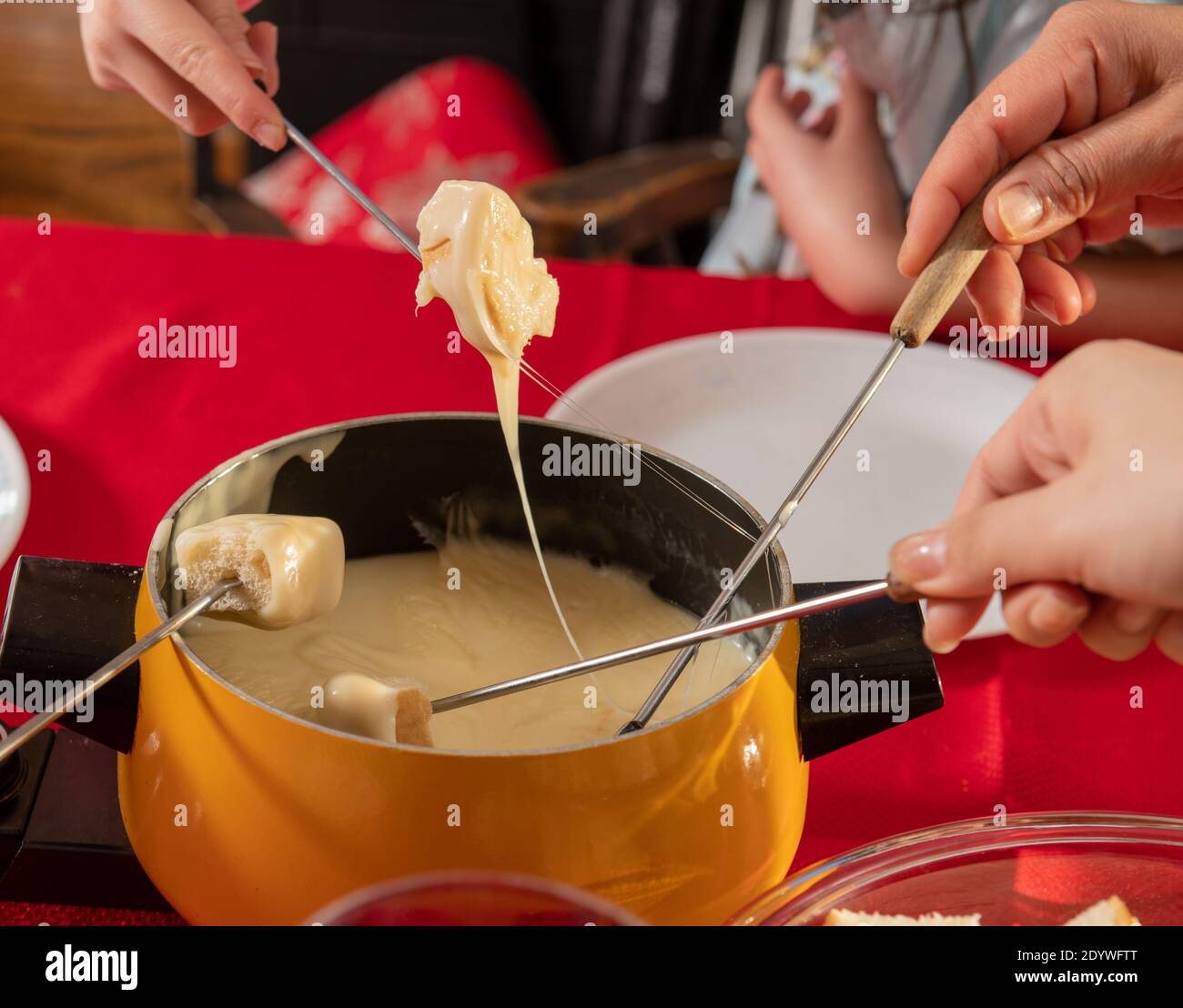 Bread being dipped in Swiss Cheese for fondue dinner Stock Photo - Alamy