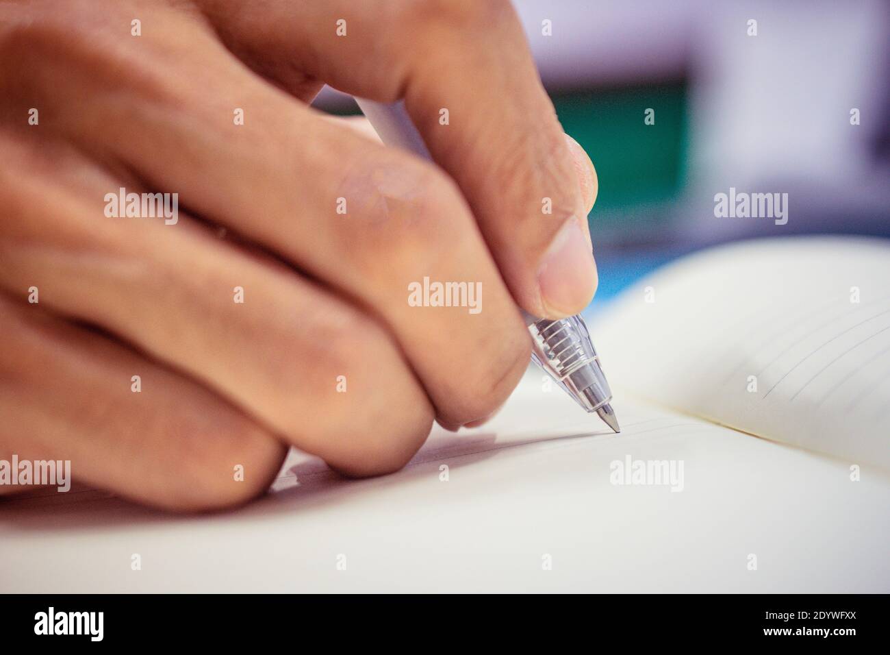 Hand holding pen and writing on book Stock Photo - Alamy
