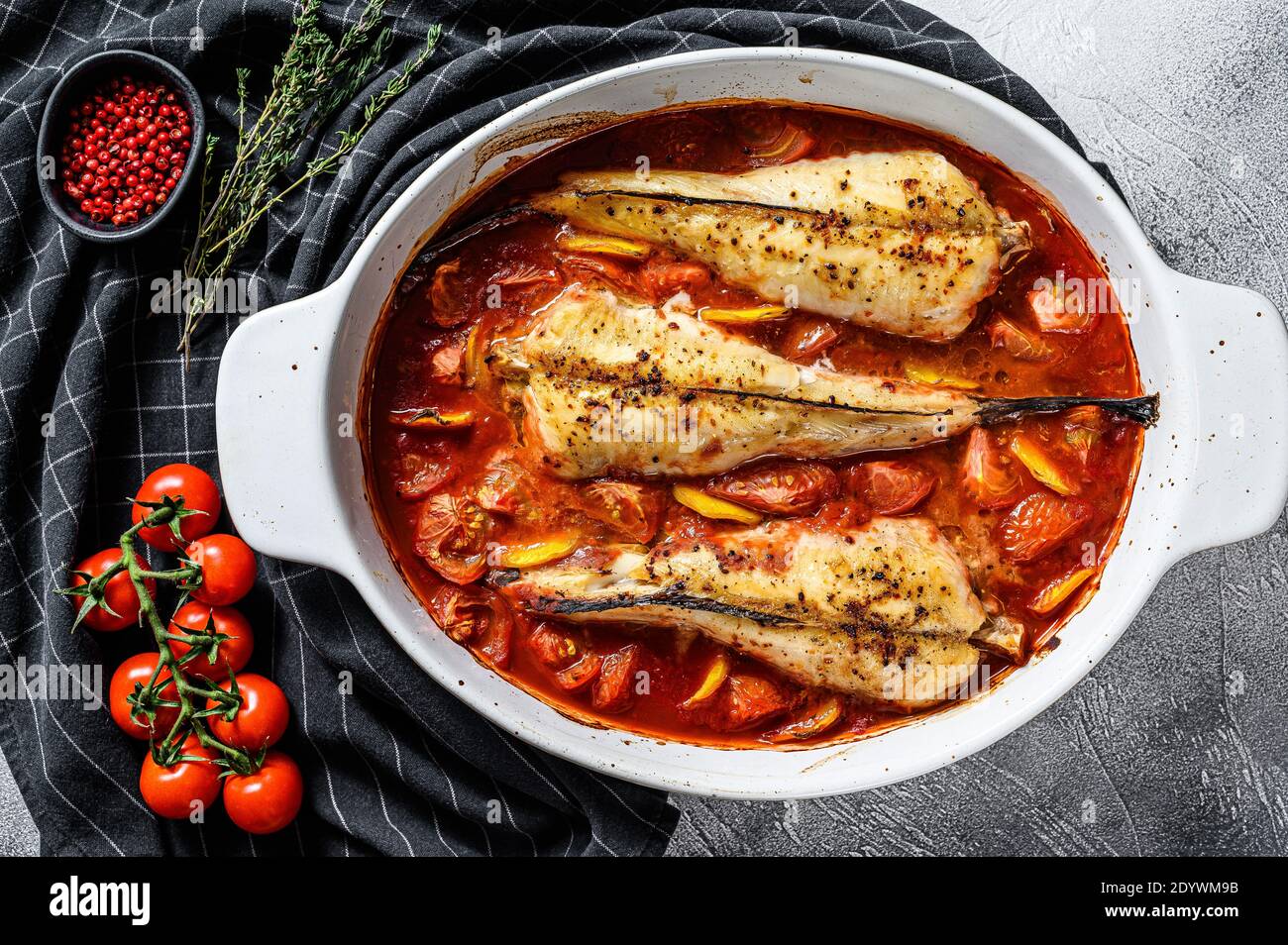 Cooking in tomatoes monkfish fish in a baking dish. Fresh seafood. Gray ...