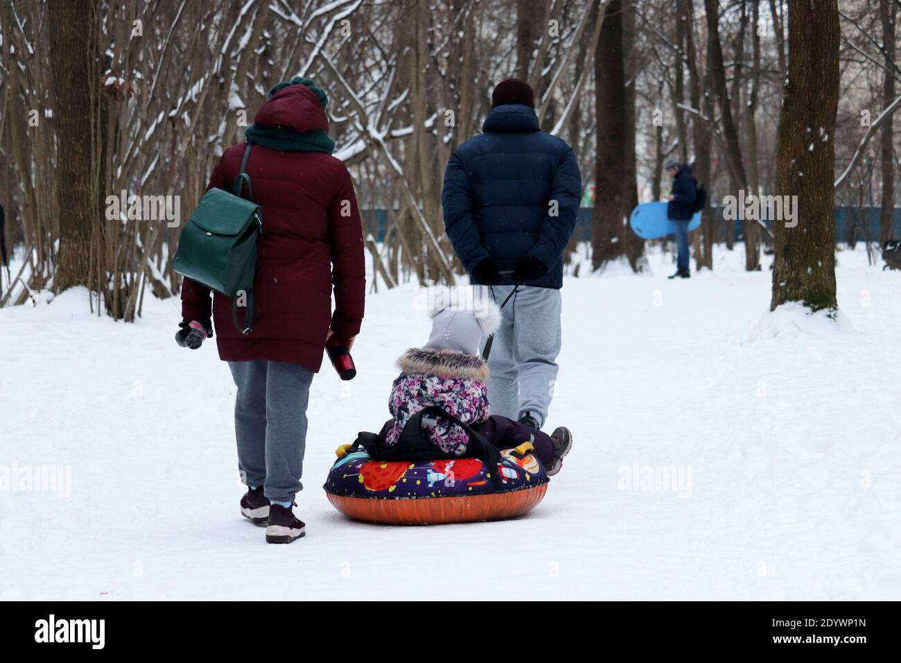 Family leisure in winter park, parents and a child on snow tube. People ...