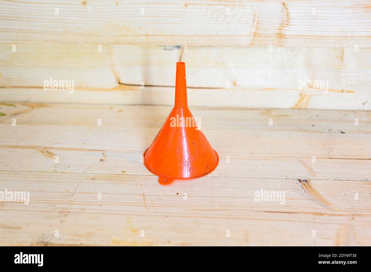 small orange plastic funnel on wooden workbench Stock Photo - Alamy