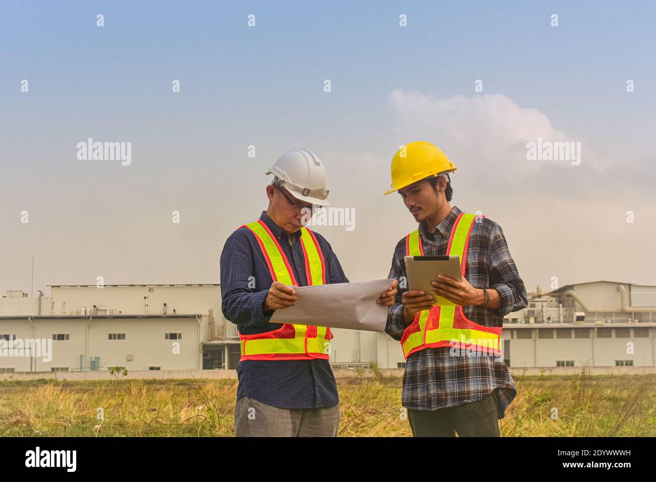 Supervisor holding blueprint talk with Foreman checking layout factory ...