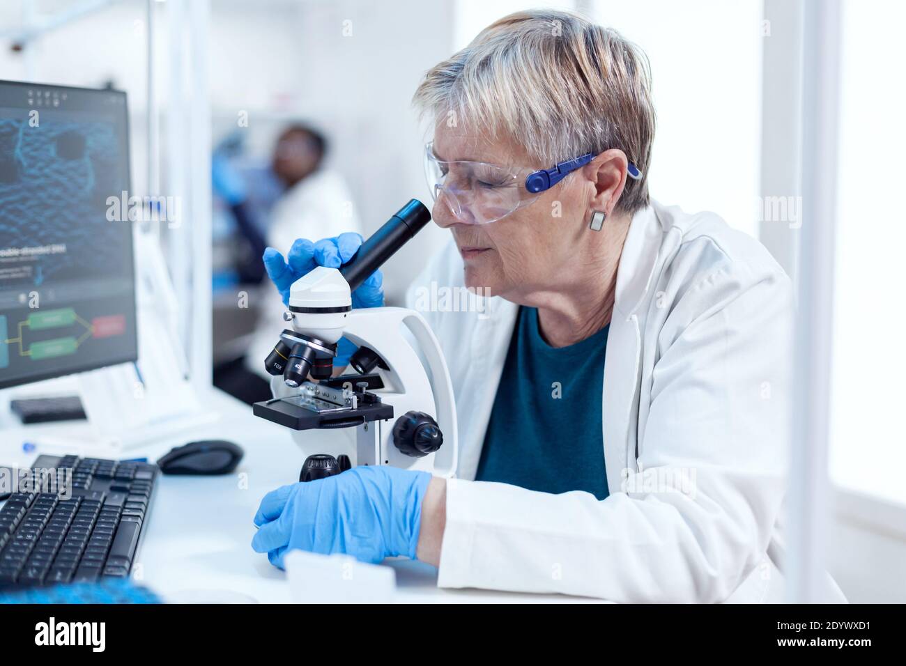 Senior chemist scientist doing genetic investigation using microscope ...