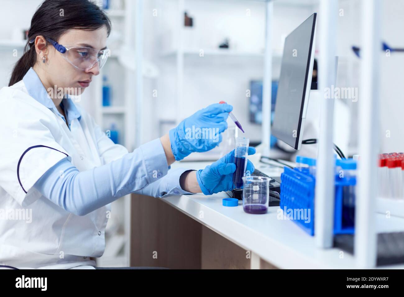 Woman scientist in lab during clinic experiement taking sample of ...