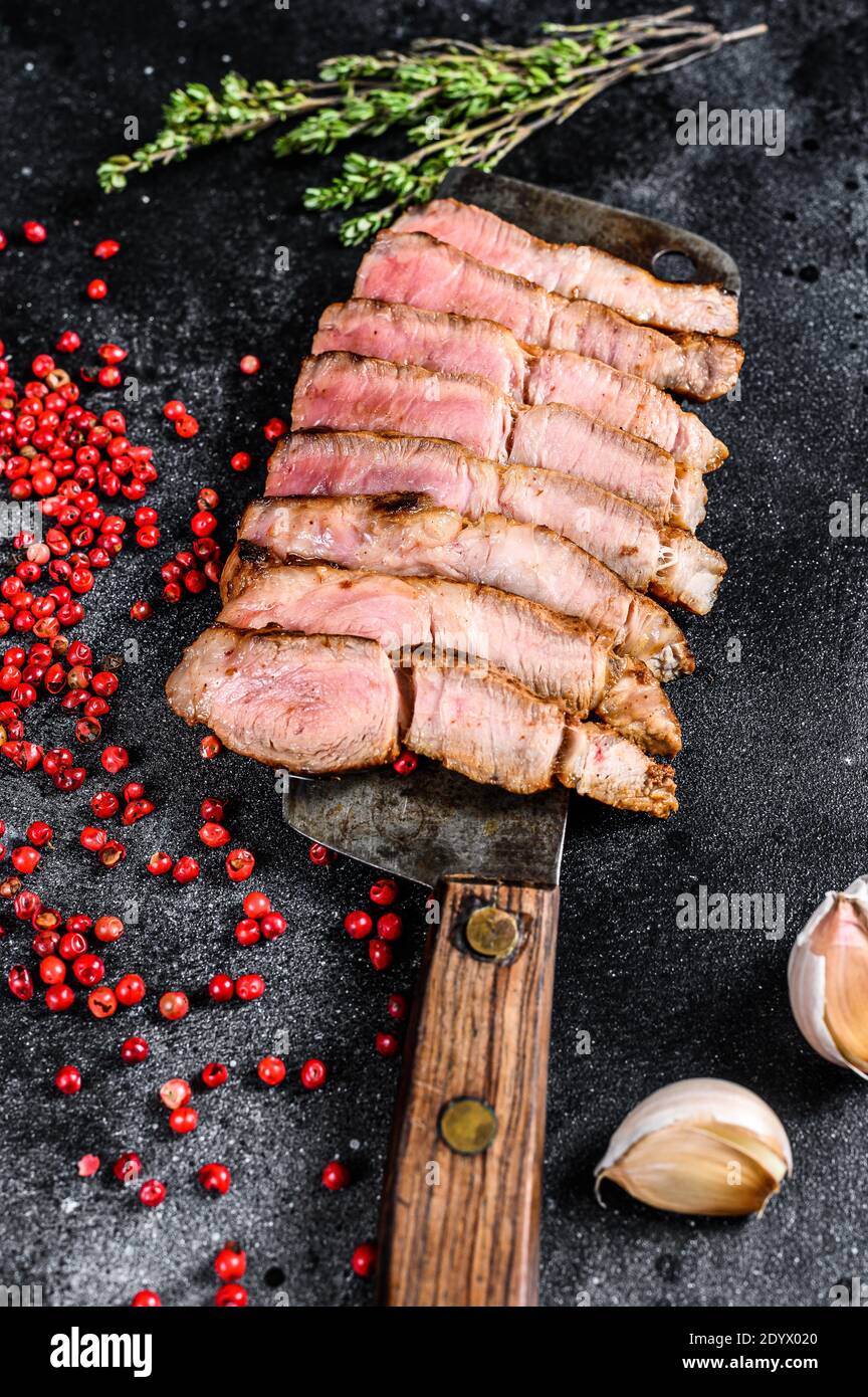 Sliced marble pork cutlet steak with spices and herbs. Black background ...