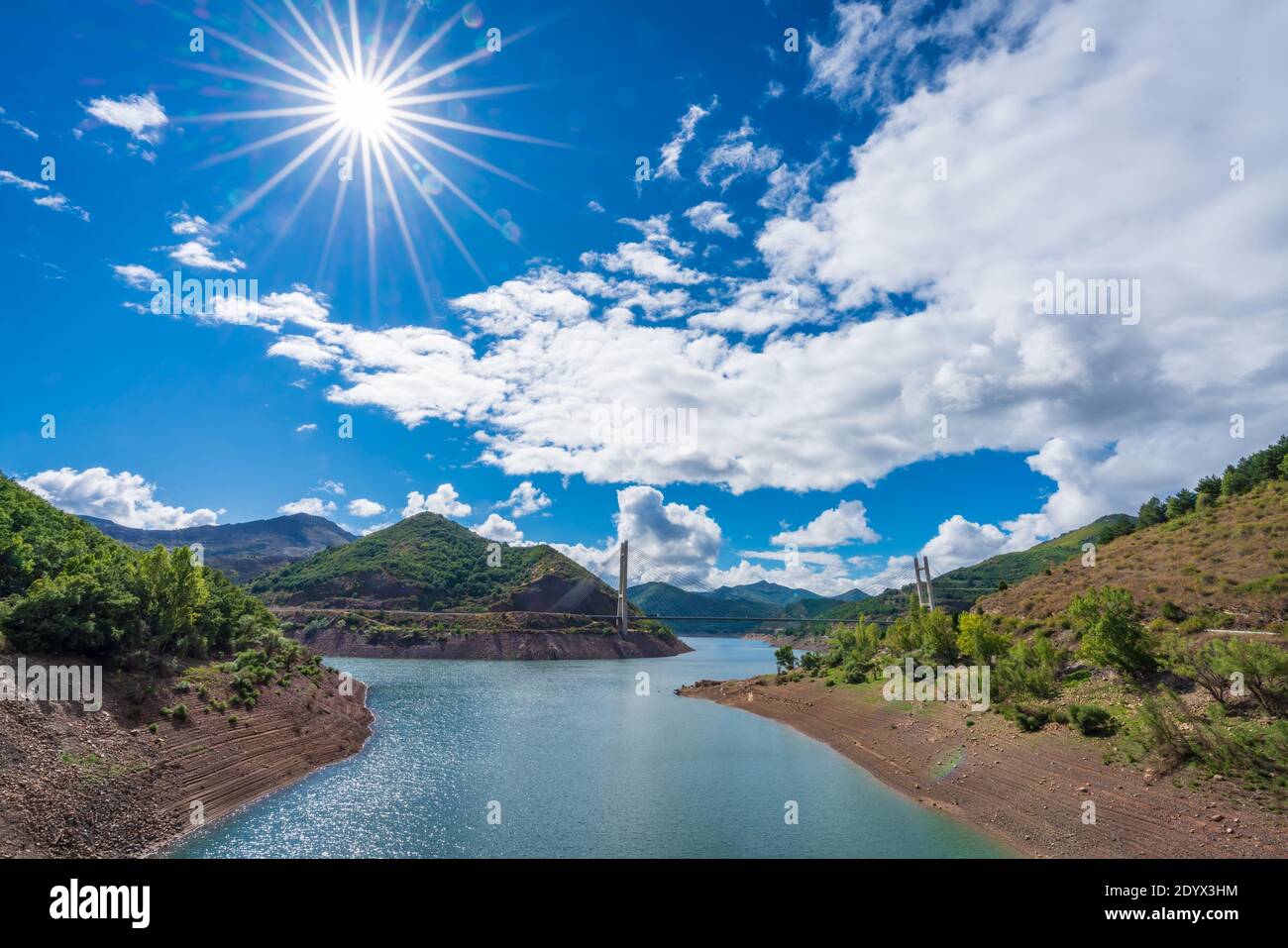 Suspension bridge over the dam with starry sun Stock Photo - Alamy